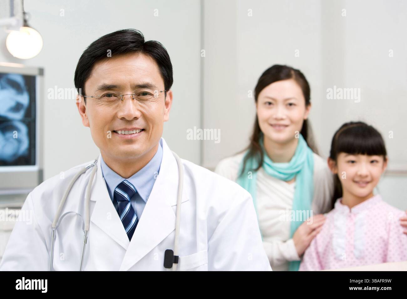 Portrait of Chinese doctor with his young patient and her mother Stock ...