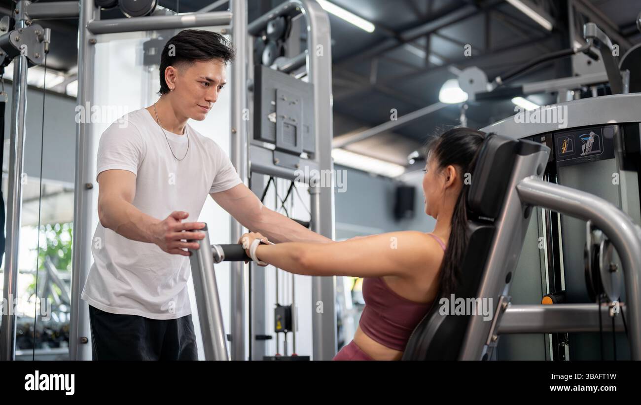 A supportive and professional Asian male fitness trainer is instructing ...