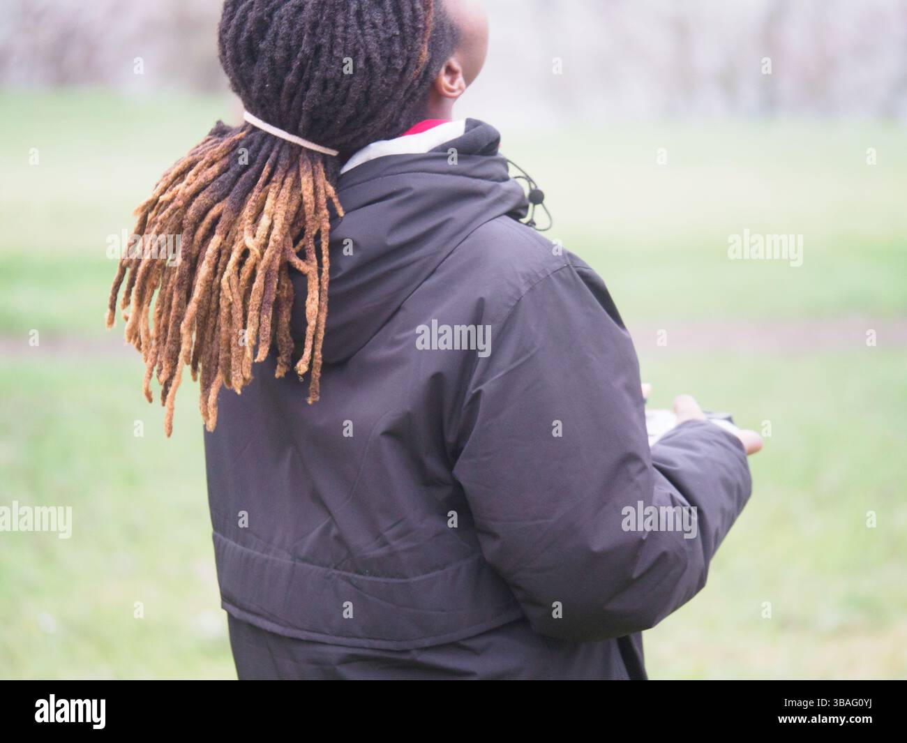 Black female teenager with dreadlocks using drone controller standing ...