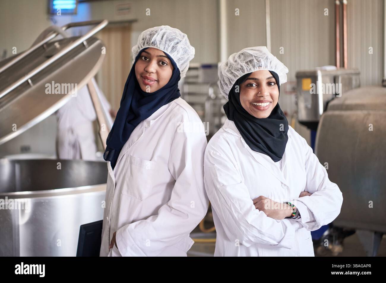 Smiling Middle Eastern female factory workers wearing hijab and white ...