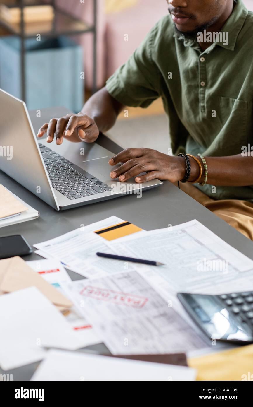 Hands of young African male economist working in front of laptop while ...