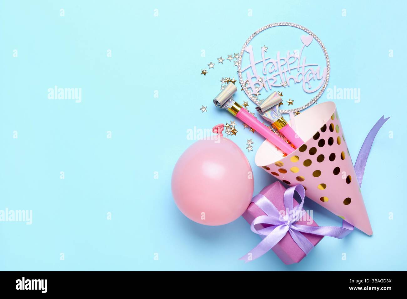 Party hat, topper, blowers, gift box and balloon on light blue ...