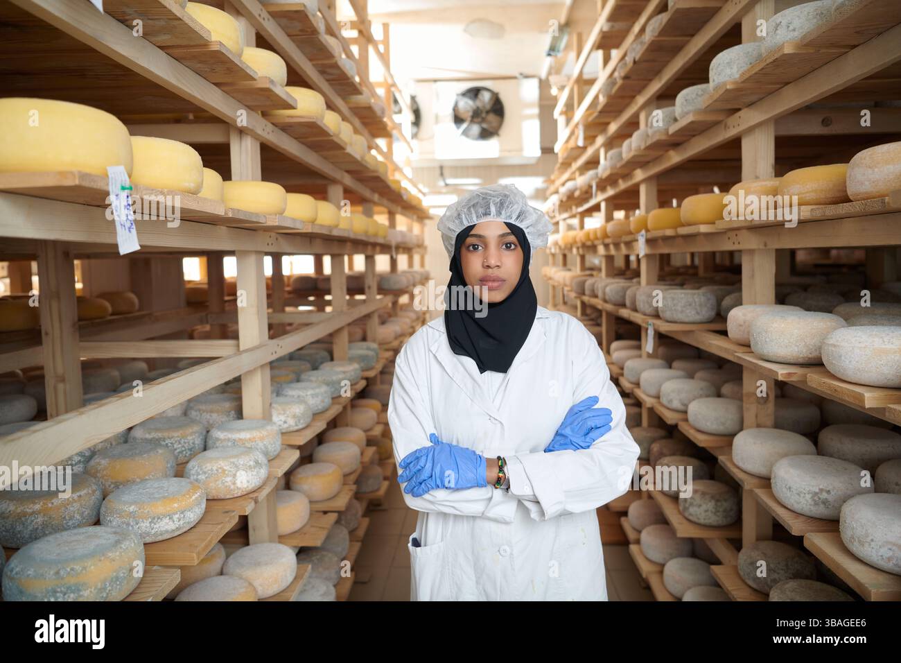 Serious Middle Eastern female worker in hijab and uniform standing with ...
