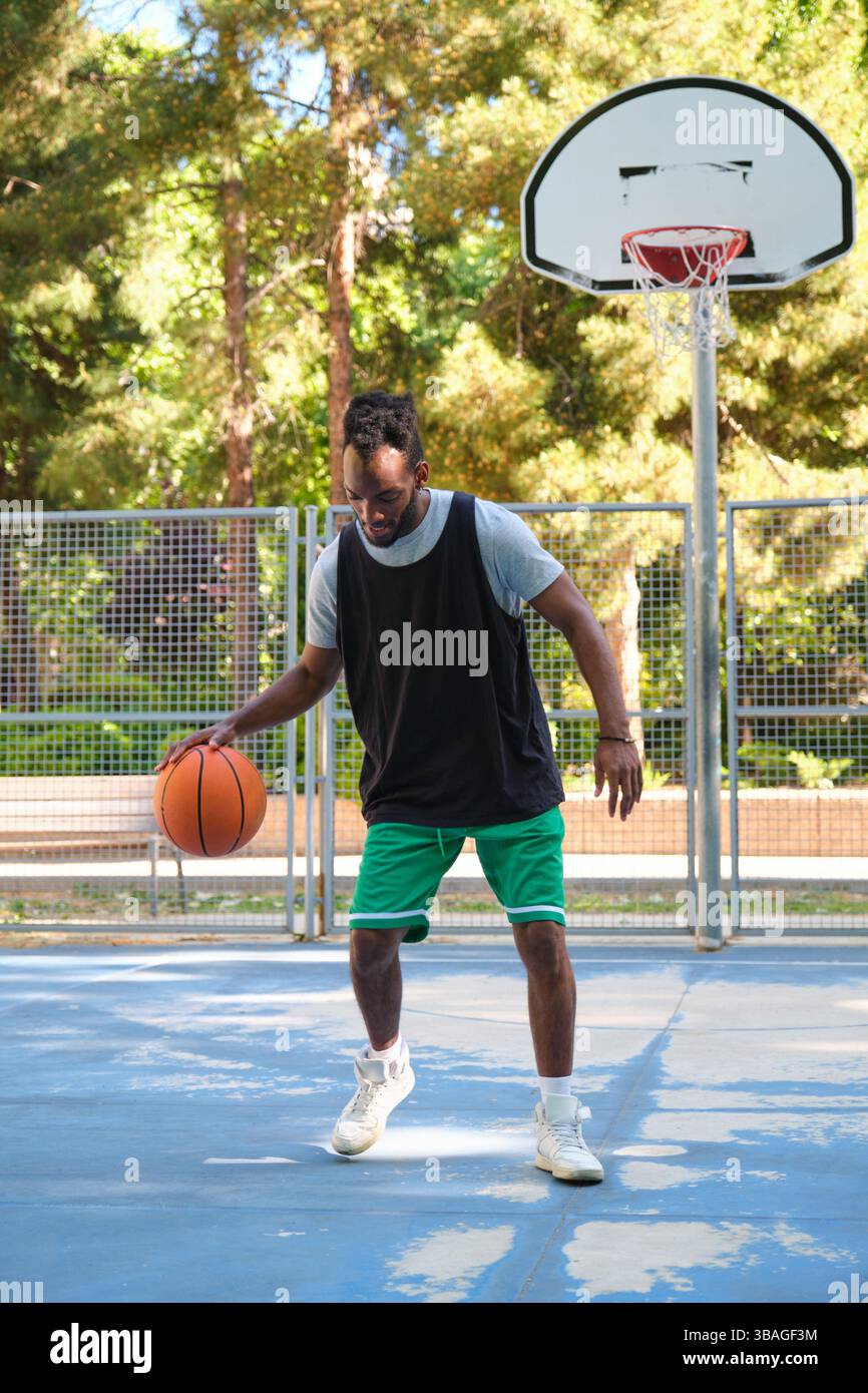 Basketball player is dribbling on an outdoor court, getting ready to ...