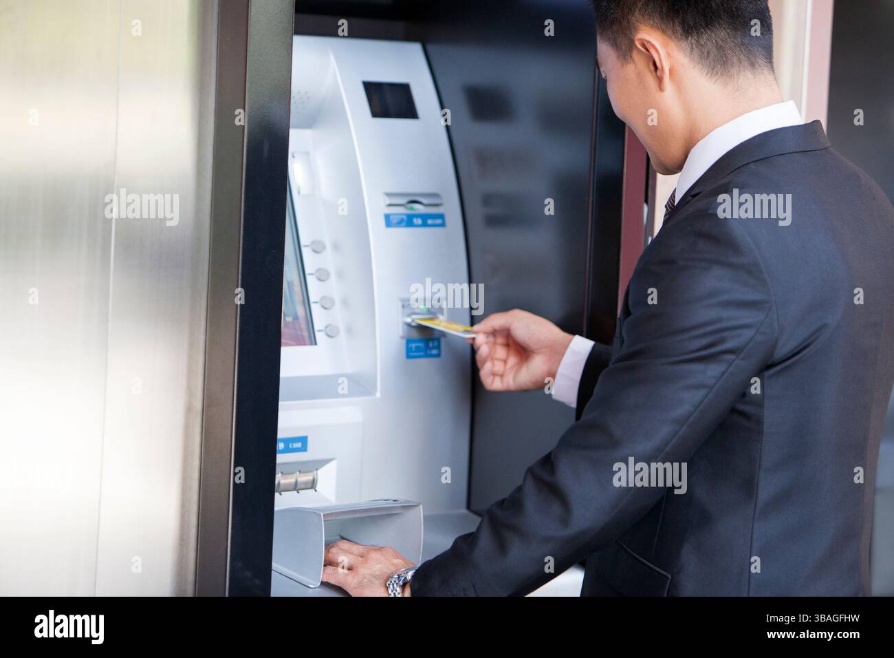 Chinese businessman using automated teller machine with bank card Stock Photo - Alamy