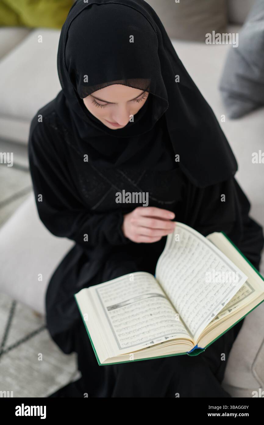 Portrait of young muslim woman reading Quran in modern home. Arabic ...