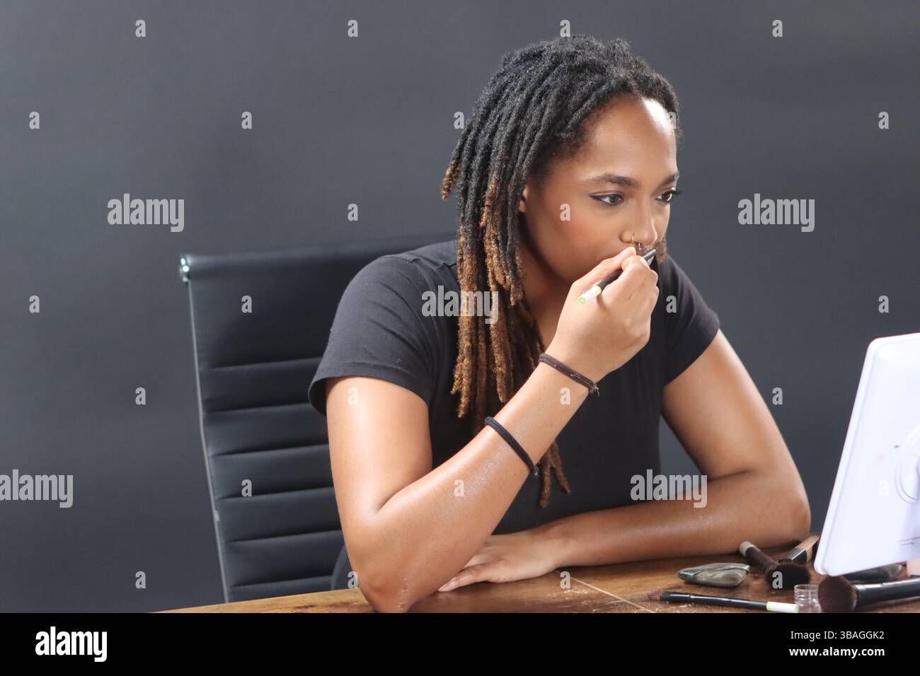Black woman in her early 20s applying makeup for a beauty tutorial ...