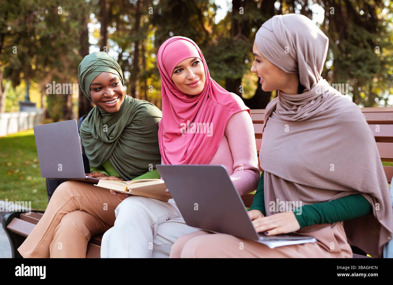 Three Modern Isamic Ladies With Laptops And Books Learning Together Talking Sitting On Bench In ...