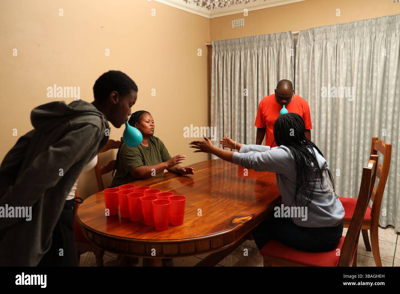 Black family having fun playing balloon cup stacking standing with ...