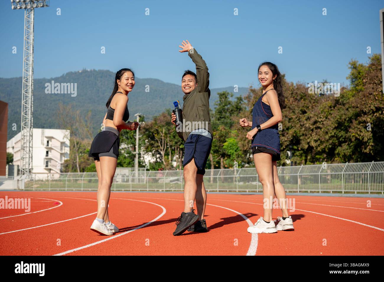 Thai male and female runners looking back and waving hand running ...