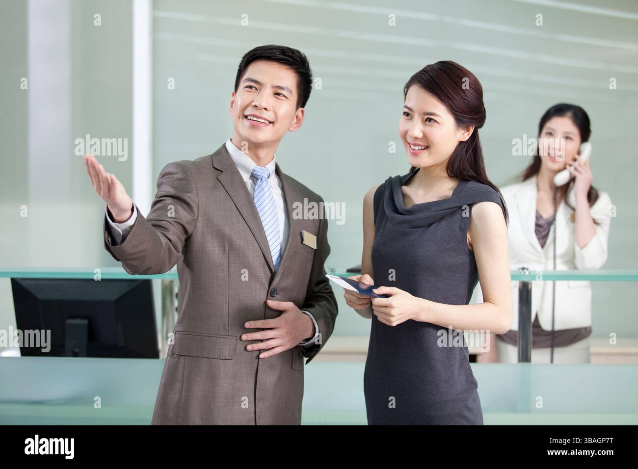 Chinese receptionist talking with businesswoman at reception desk Stock ...