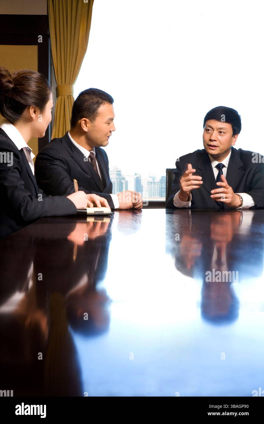 Three Chinese business professionals around conference table Stock ...