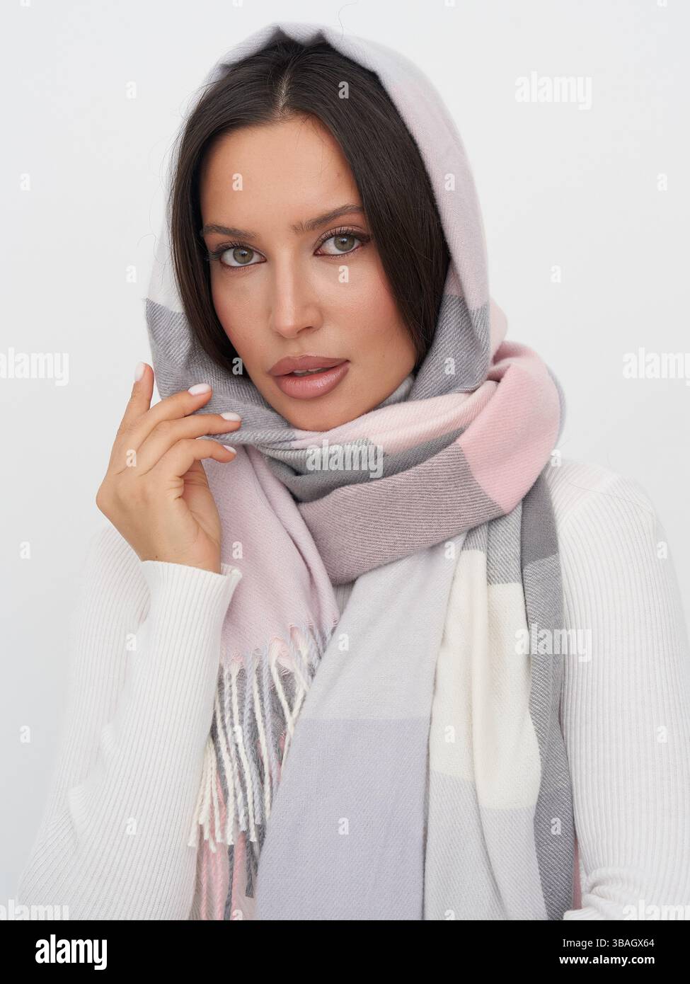 Woman wearing a stylish scarf poses against a light background in a ...