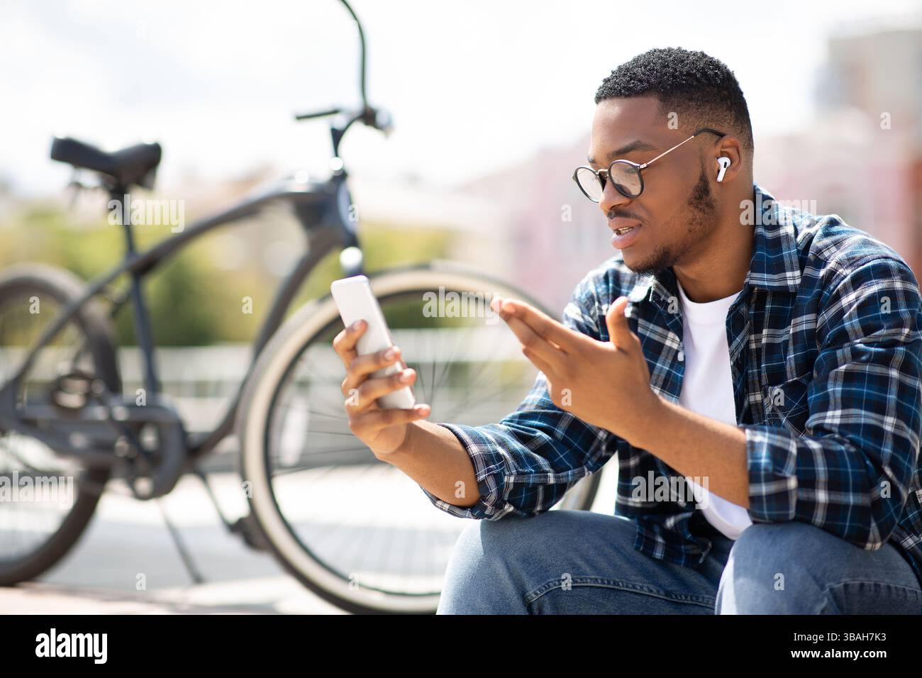 Portrait of Black hipster making video call using cell phone, sitting ...