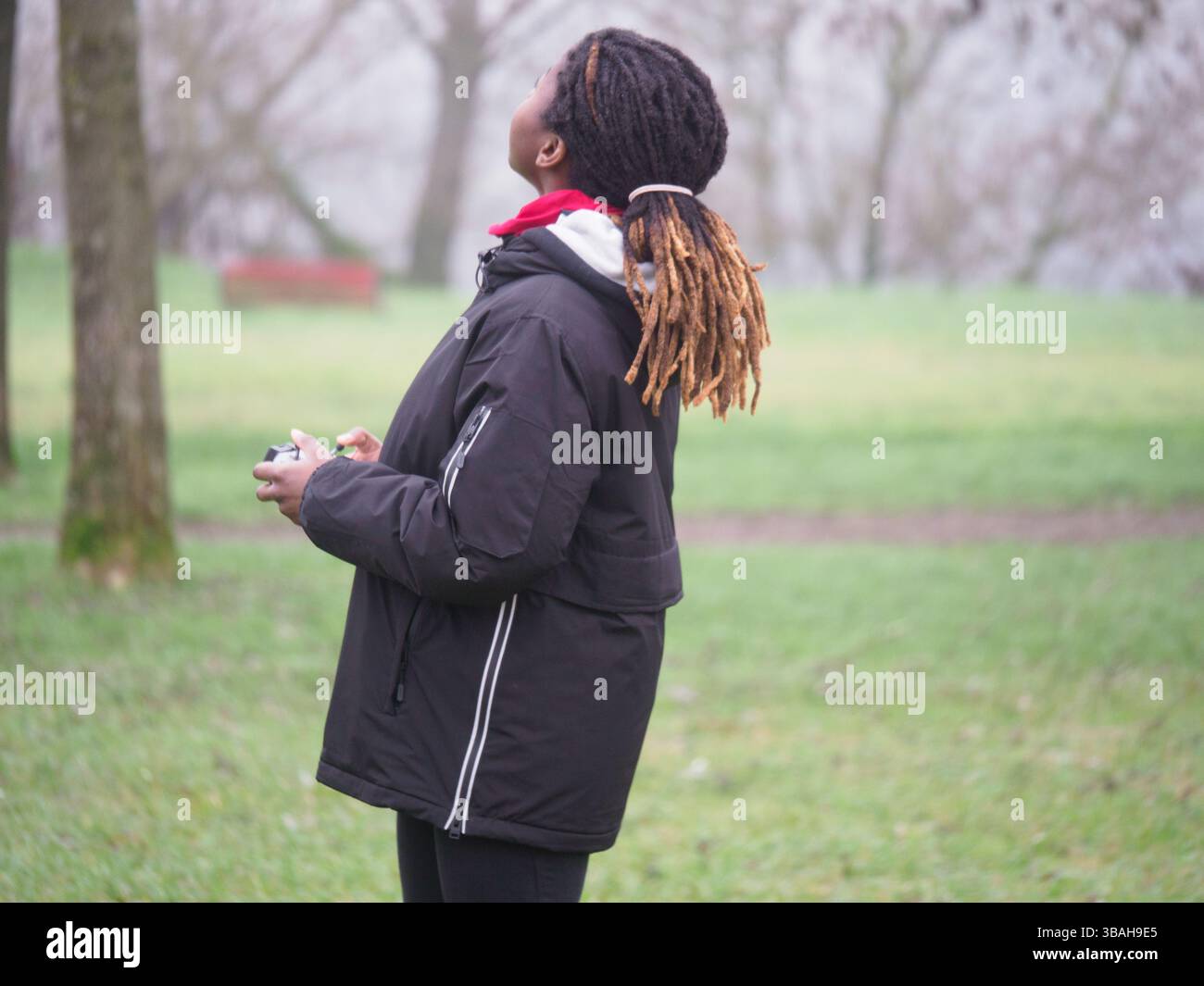 Black female teenager with dreadlocks using drone controller standing ...