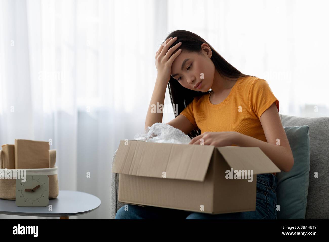 Wrong package. Upset asian woman unpacking box, shocked by bad delivery ...