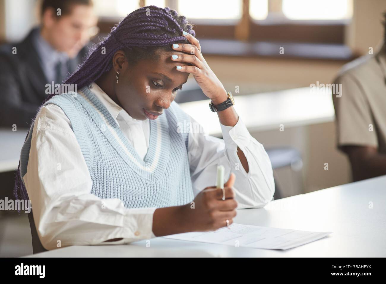 Black female student with purple braids taking exam thinking while ...