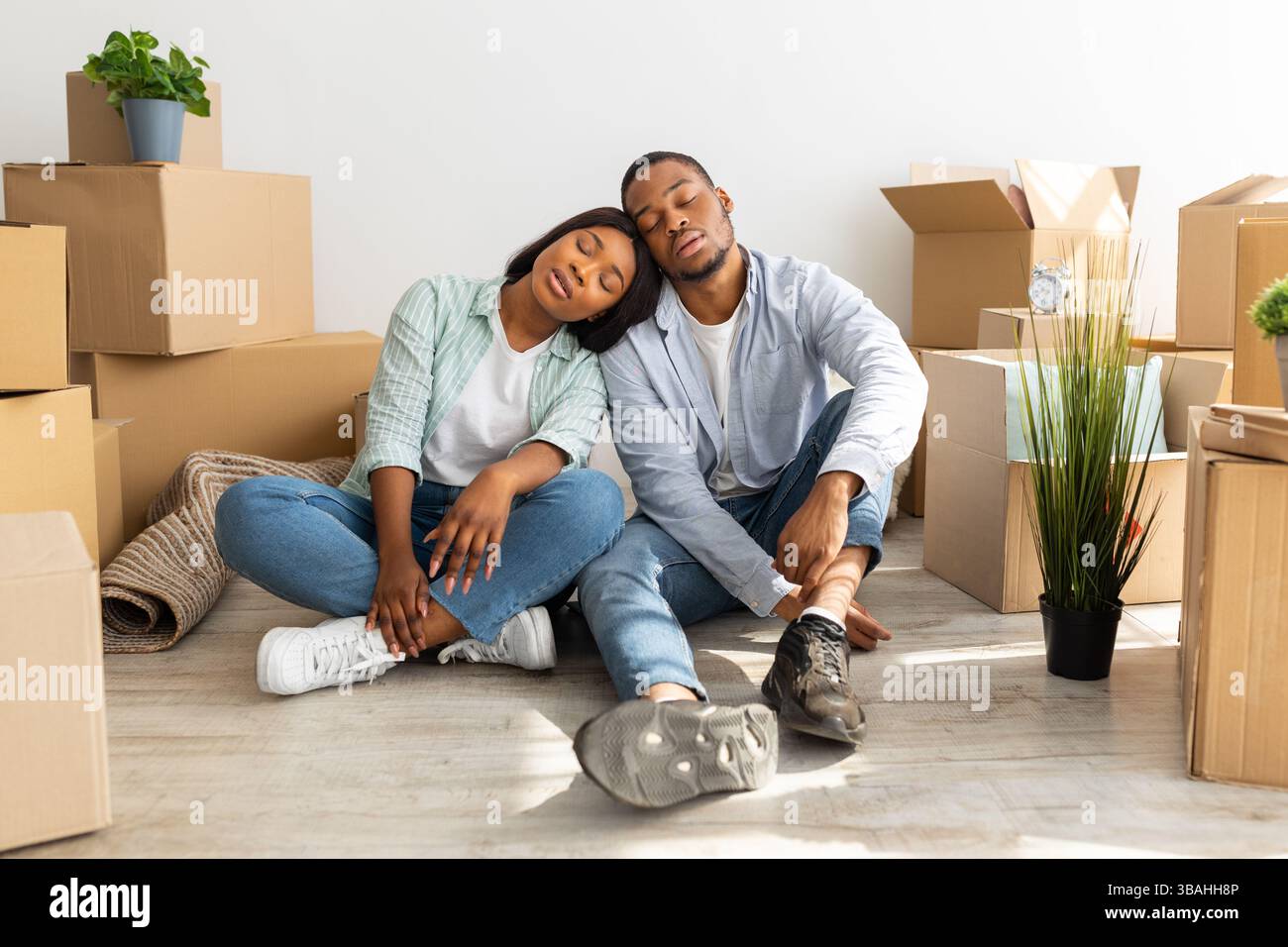 Sad black family sitting on floor with cardboard boxes around, being ...