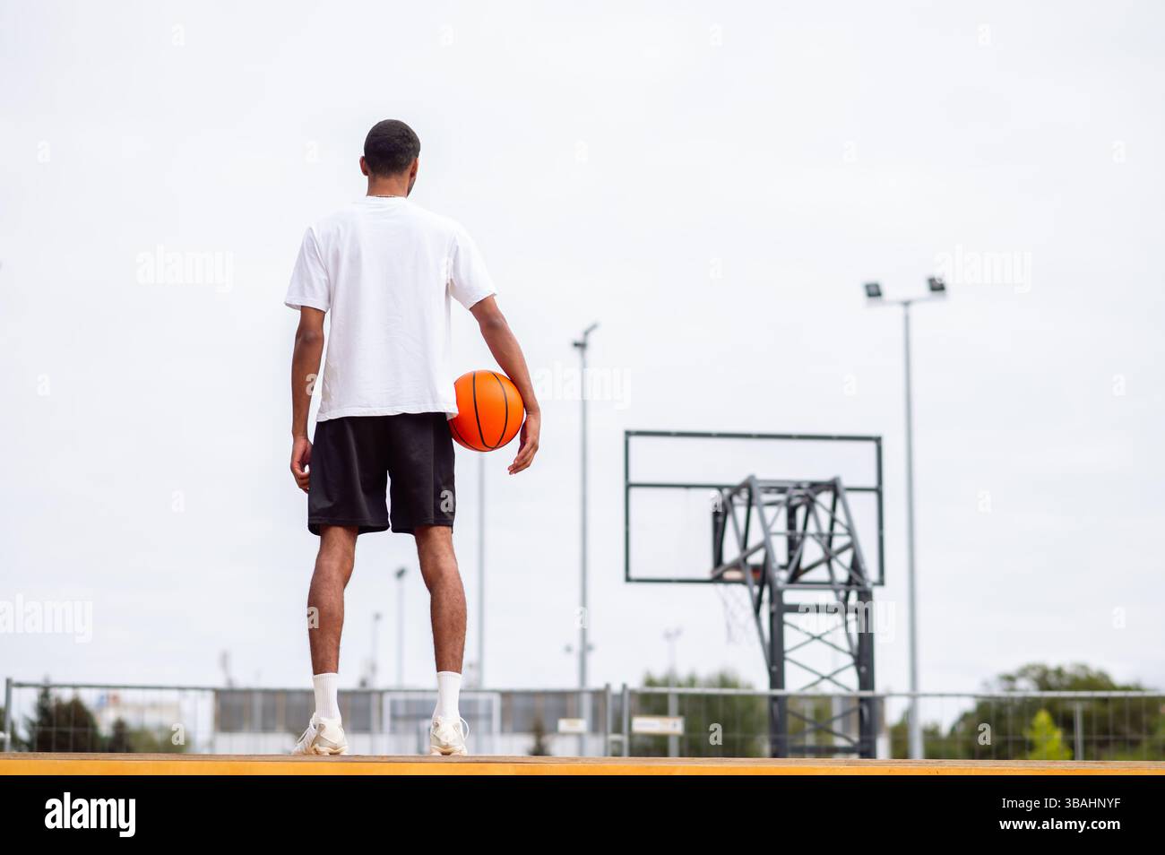Basketball. Tall man in sportswear standing with a ball in hands near ...