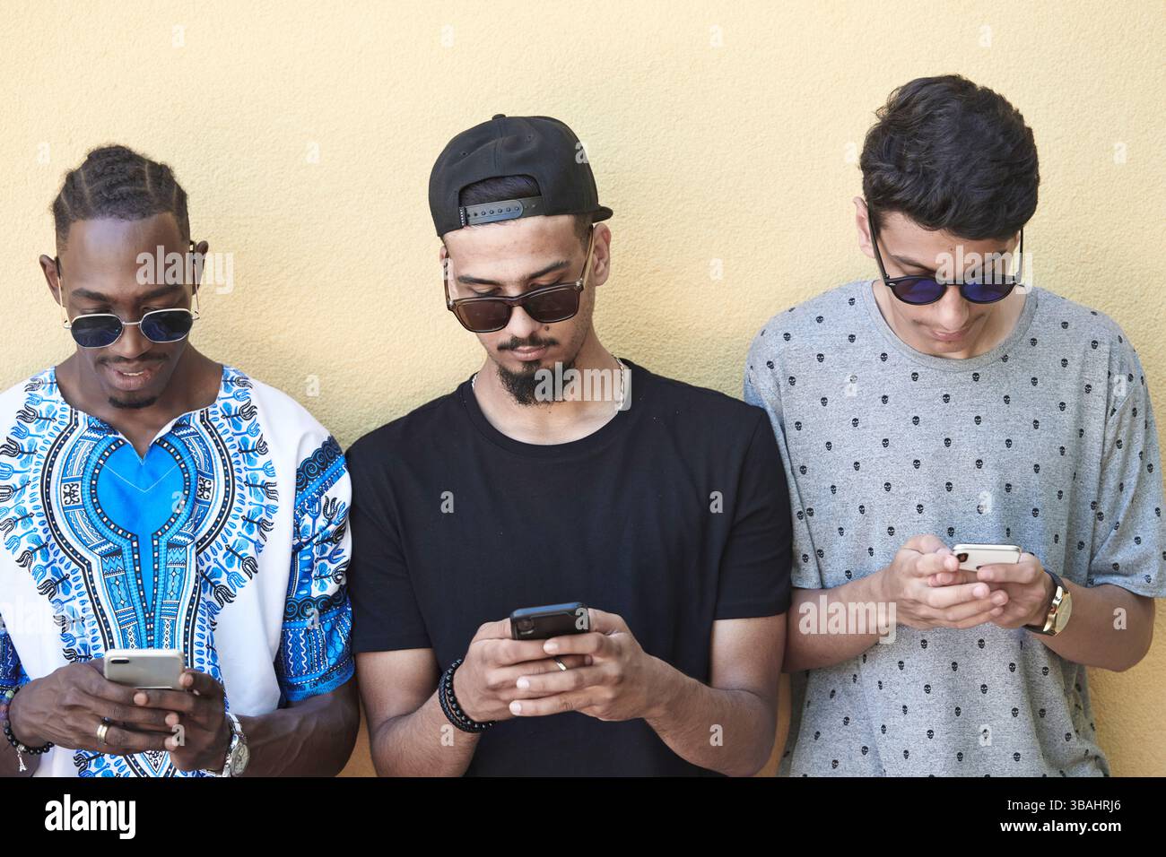 Serious Black and Middle Eastern men using their smartphones while ...