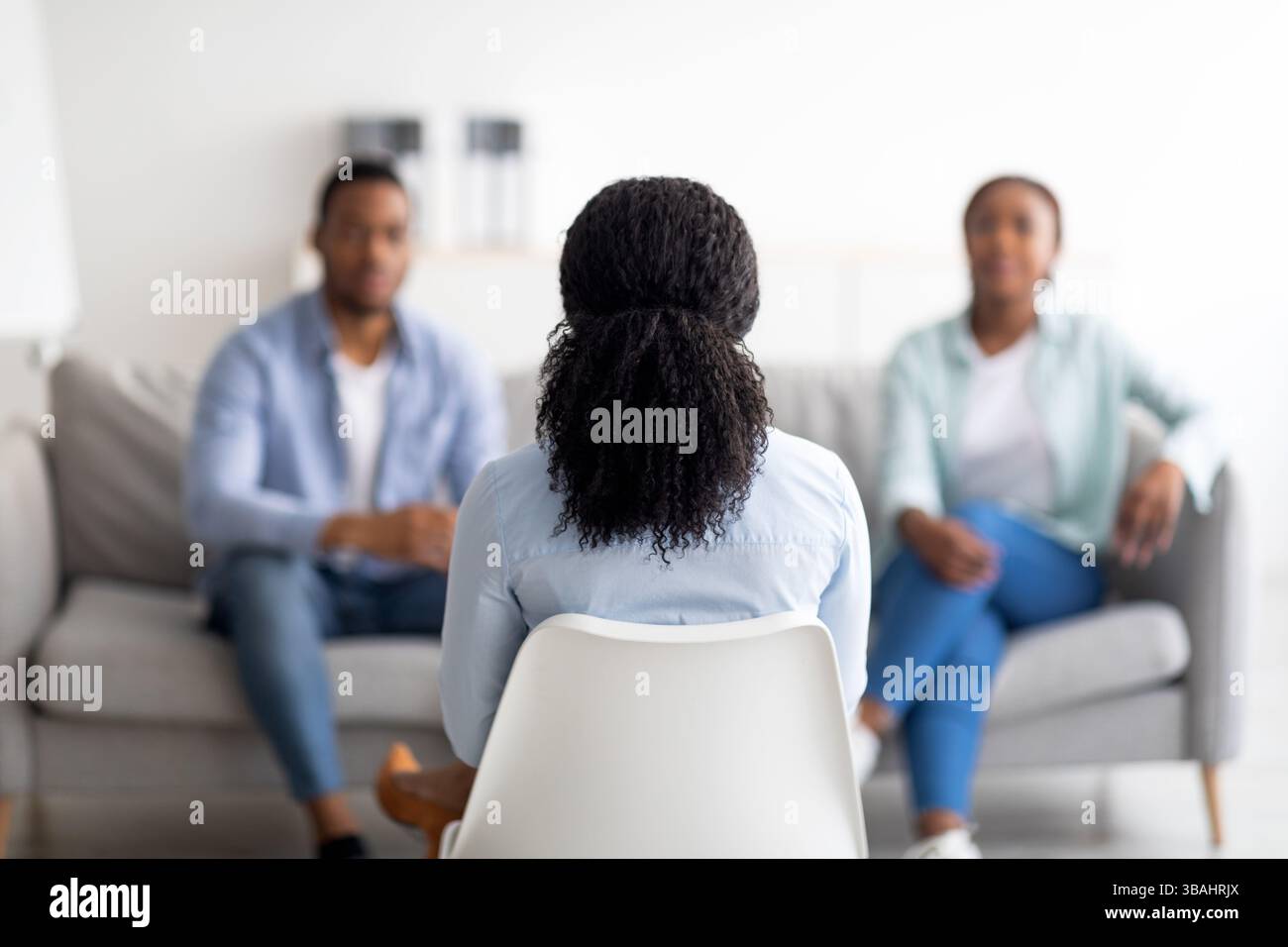 Female psychologist sitting with her back to camera, consulting ...