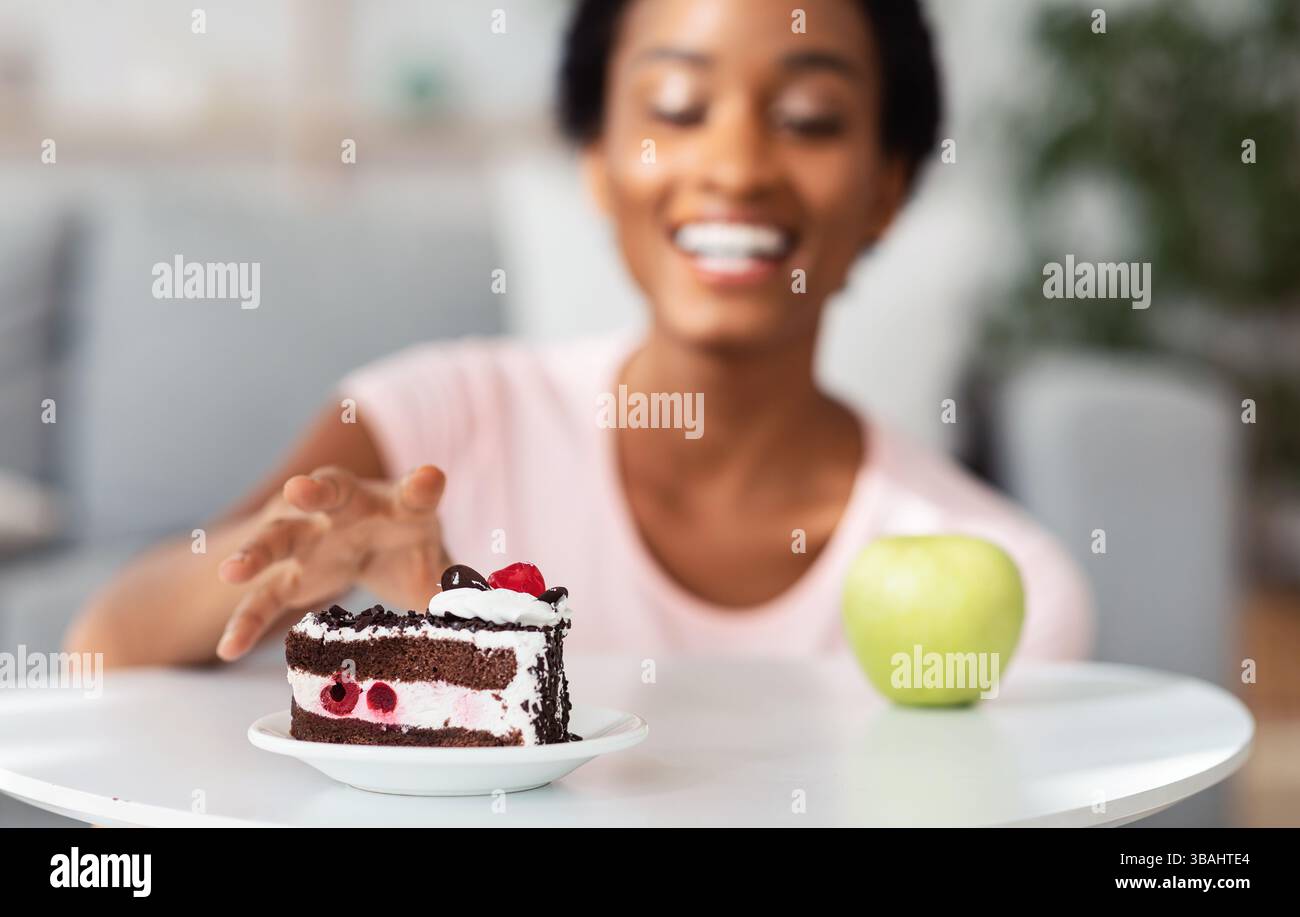 Diet breakdown concept. Young black lady reaching for cake instead of ...