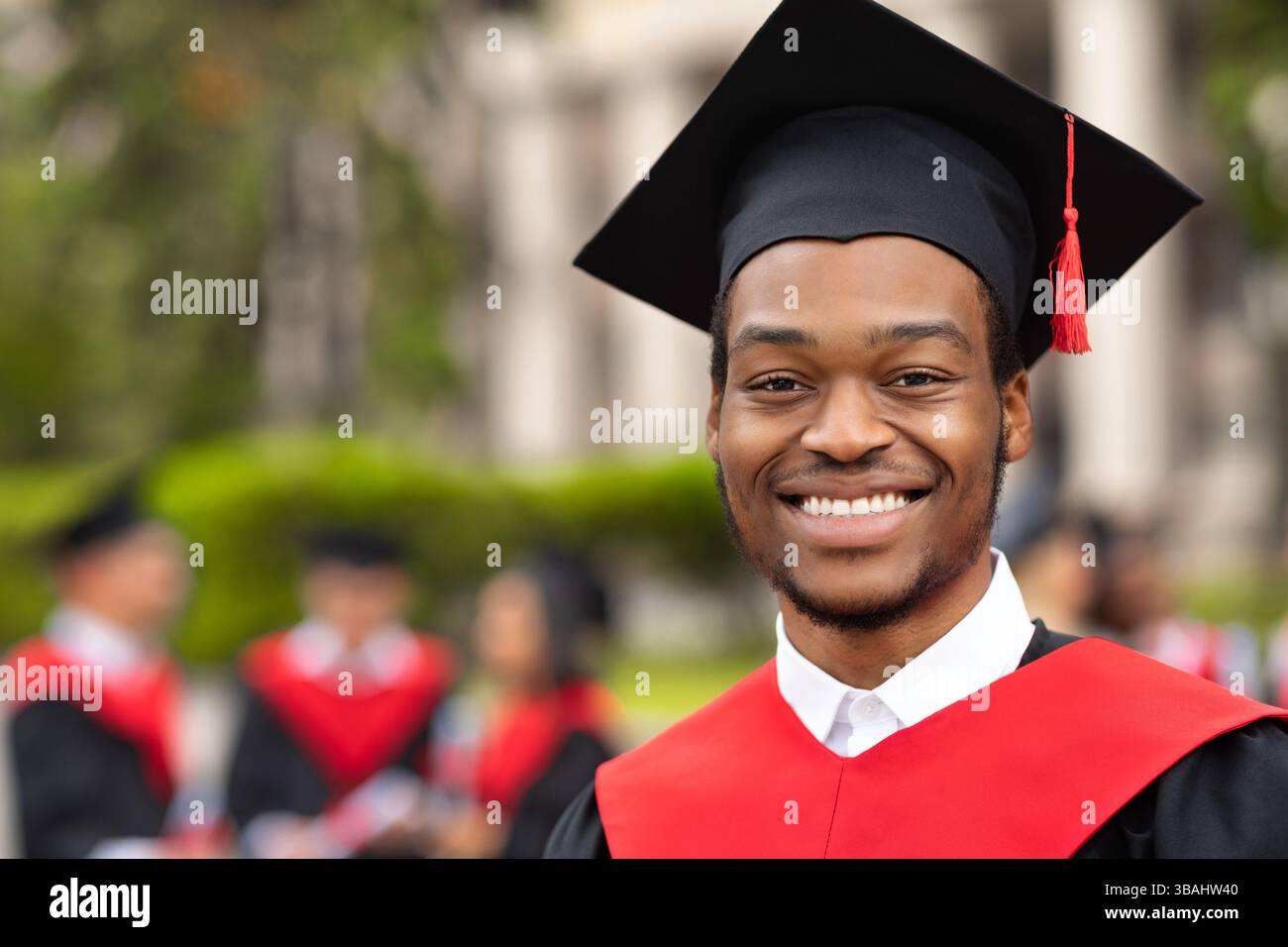 Black male student wearing graduation gown and cap standing near ...