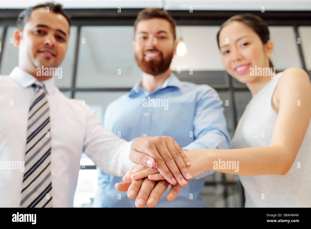 Happy excited business colleagues stacking hands to express unity before starting work on new ...