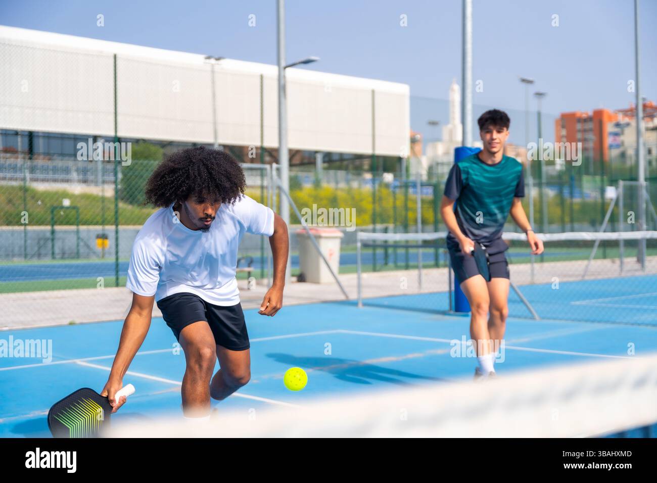 African man making an effort to reach pickleball ball playing with ...