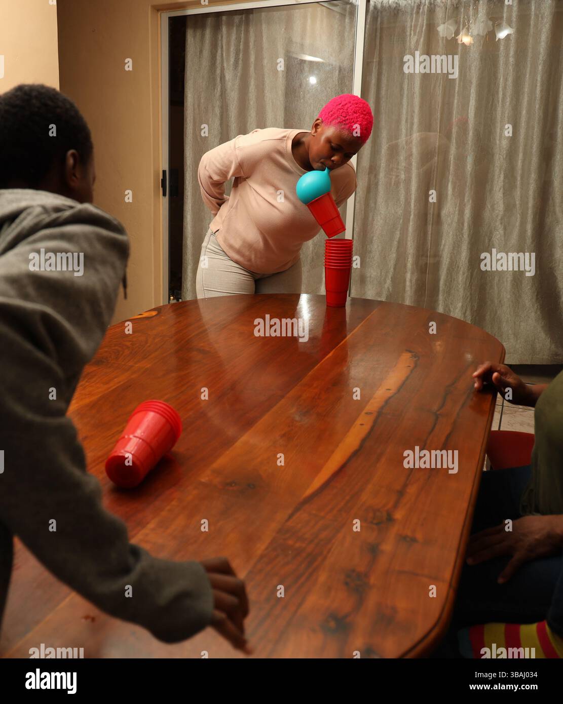 Black female teenager with pink hair hands behind back playing balloon ...