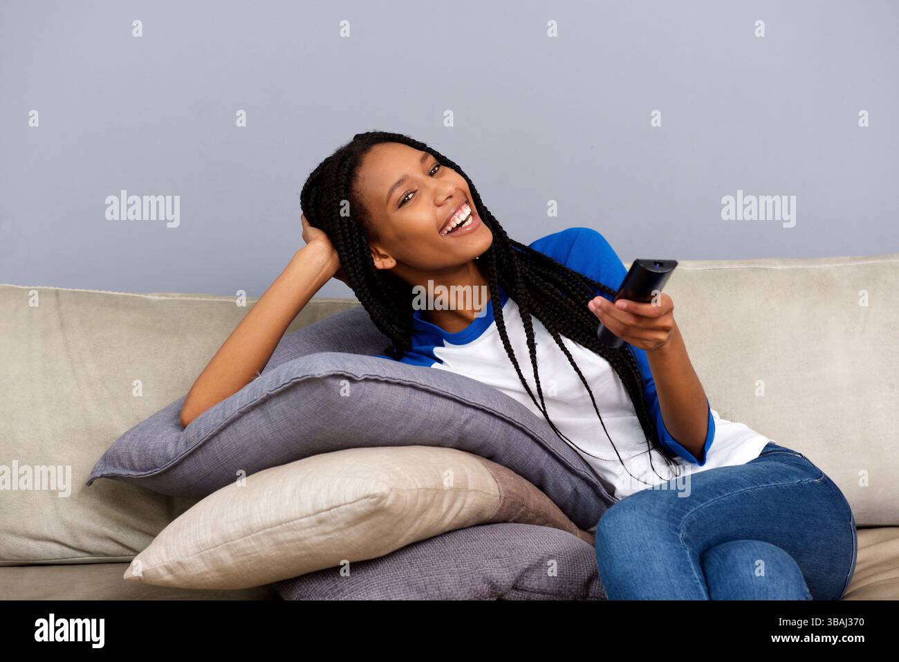Portrait of happy african american girl holding remote control sitting ...