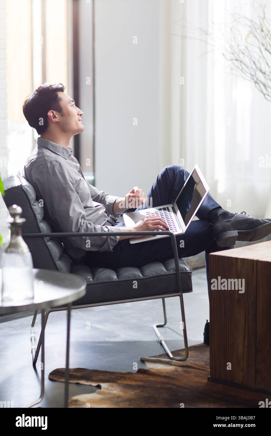 Young Chinese man working with laptop in office Stock Photo - Alamy