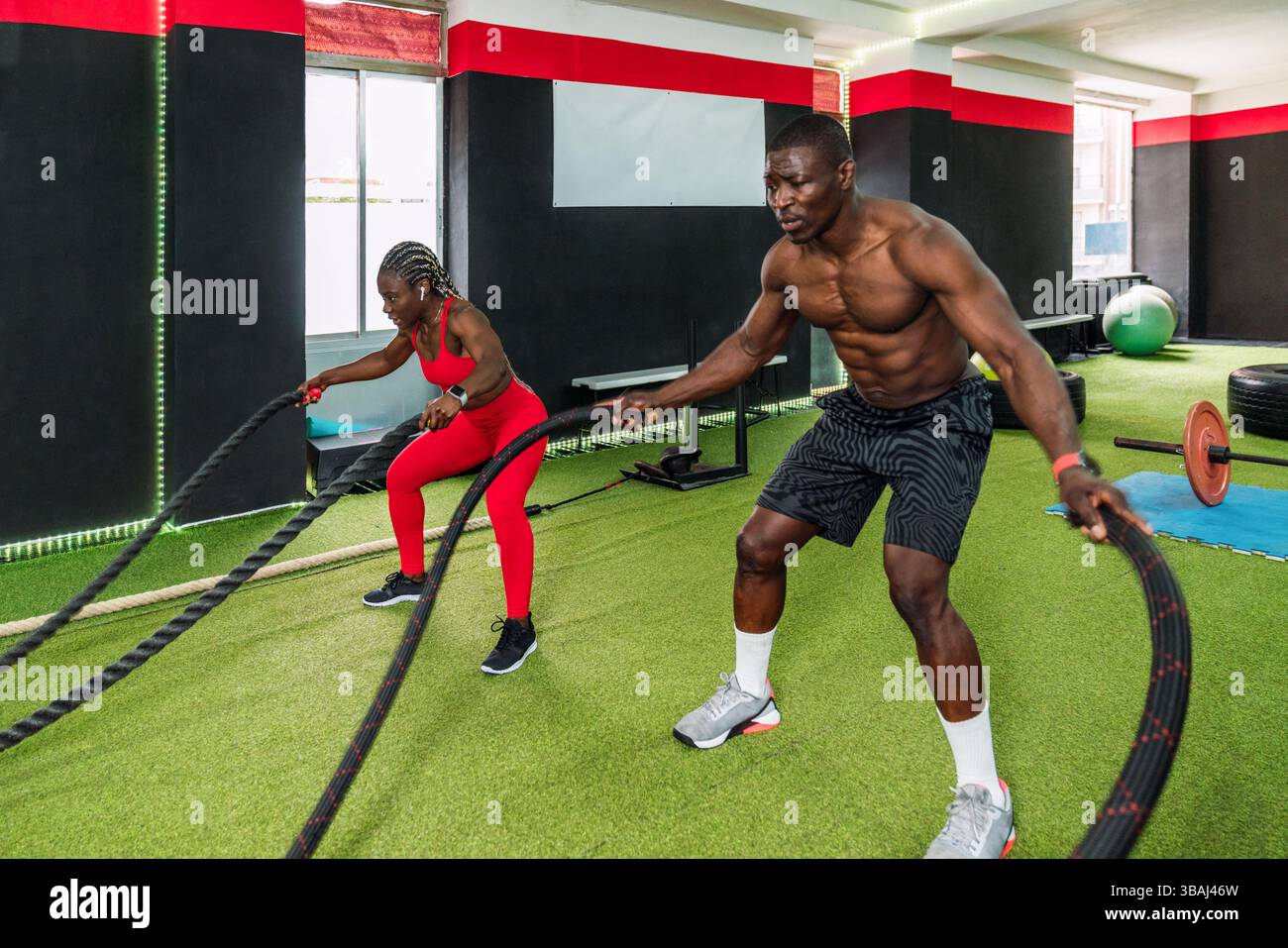 Two black bodybuilder athletes in a sports gym doing an aerobic rope ...