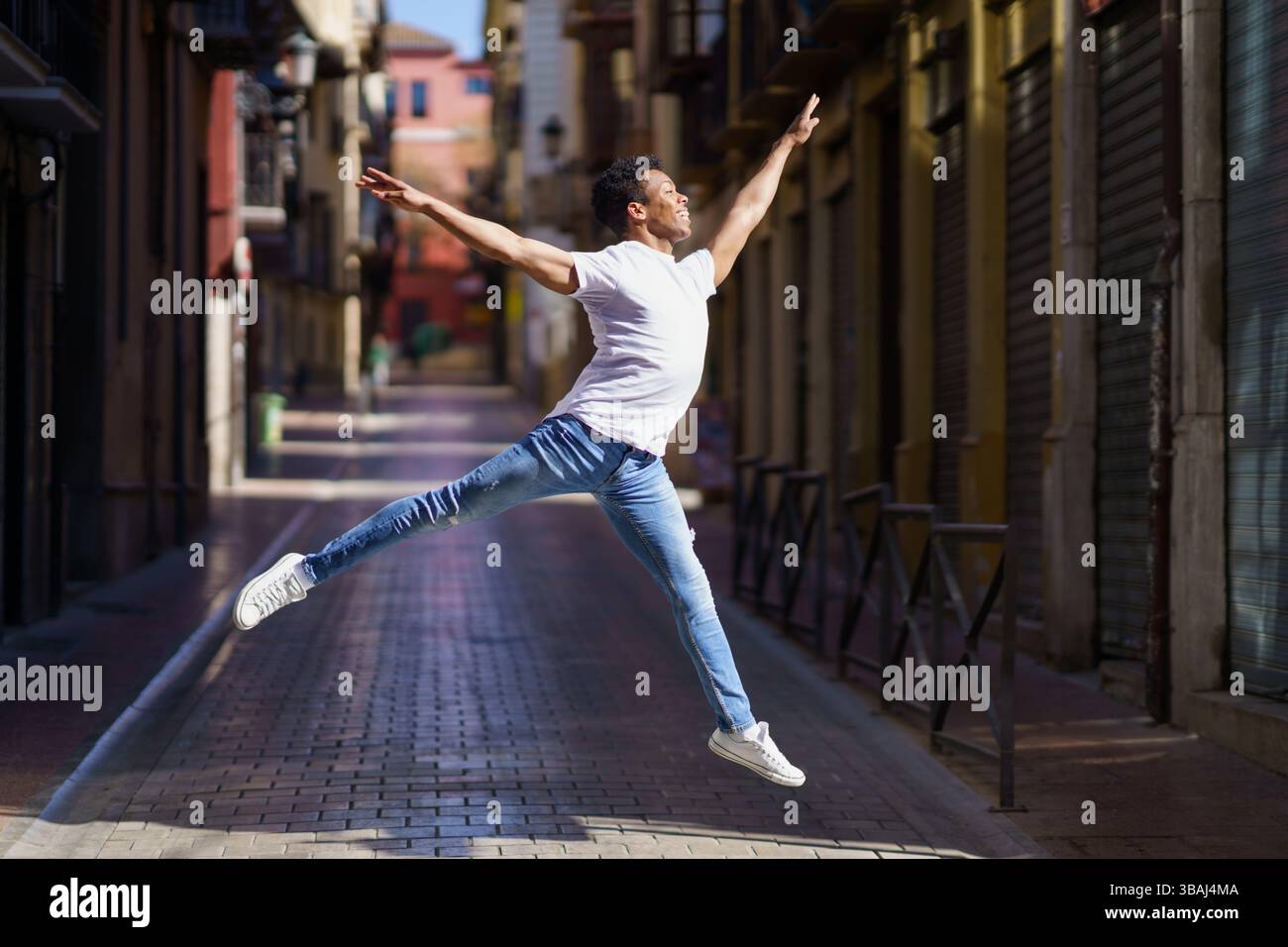 Black male doing an acrobatic jump on city street on sunny day Stock ...