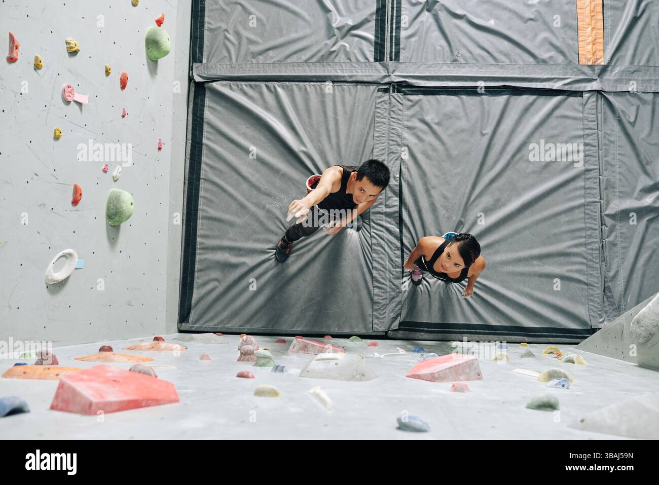 Climbing wall instructor explaining Asian woman how to climb bouldering ...