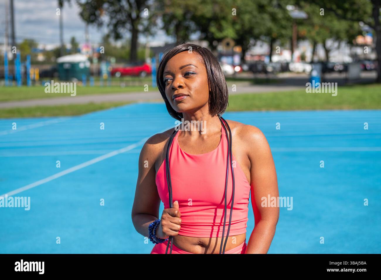 Serious Black woman in pink activewear looking away while standing with ...