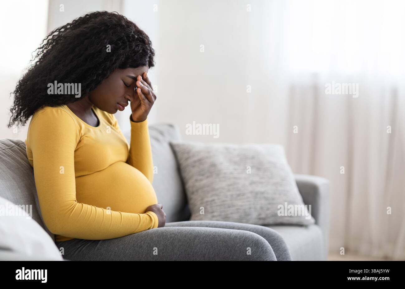 Young pregnant black woman suffering from headache or migraine, feeling ...