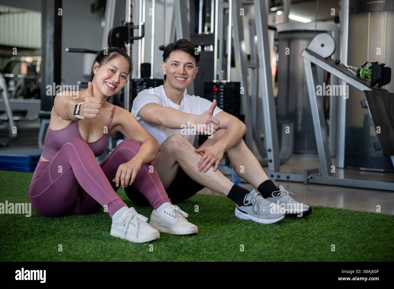 Asian male and female in sportswear are sitting on the floor of a ...