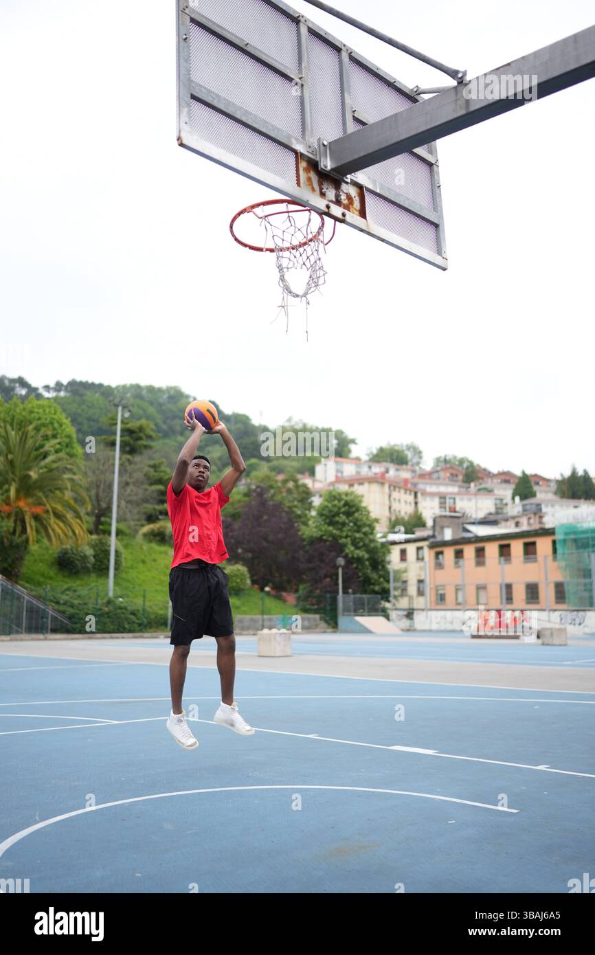 Vertical photo of a basketball player throwing a ball in an outdoor ...
