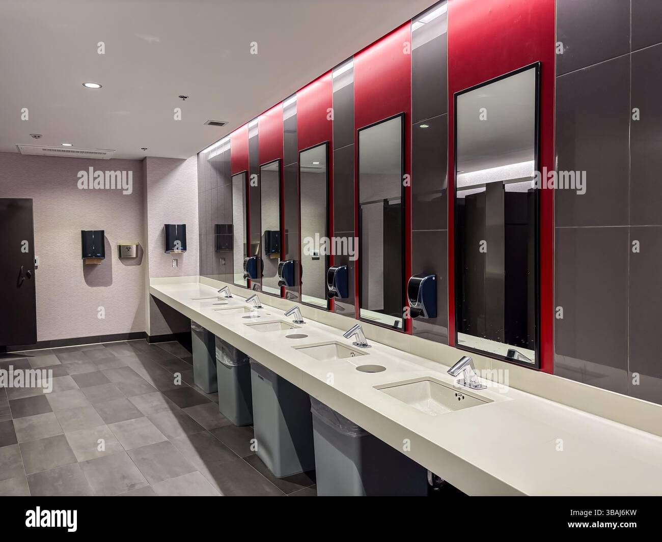Modern public washroom with a long countertop, multiple sinks, mirrors ...