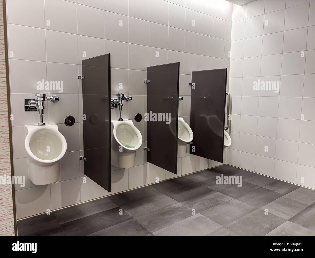 Men's washroom with multiple urinals and privacy dividers in a public ...