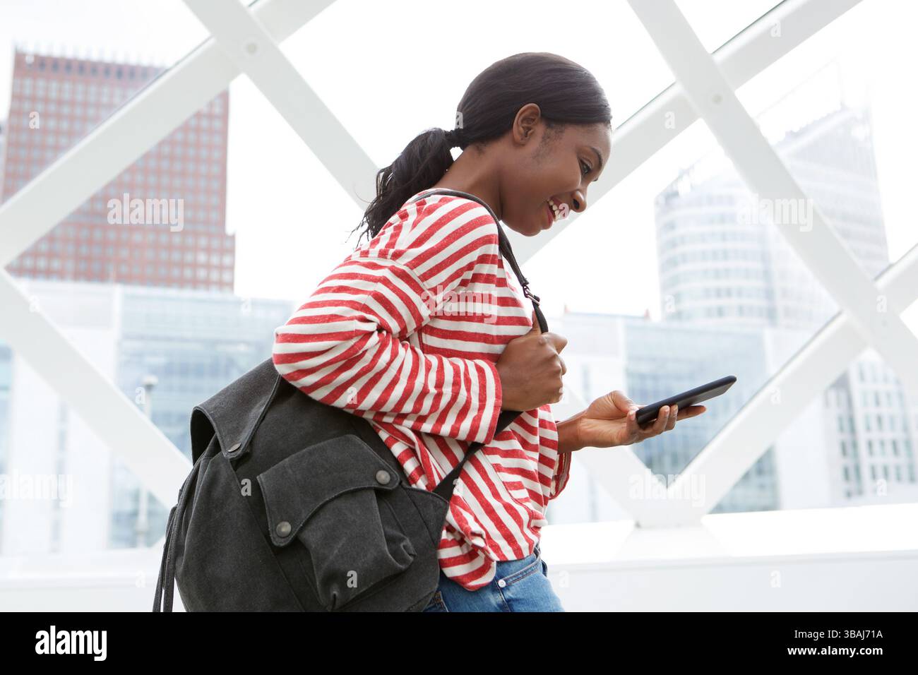 Black woman texting while walking during daytime Stock Photo - Alamy