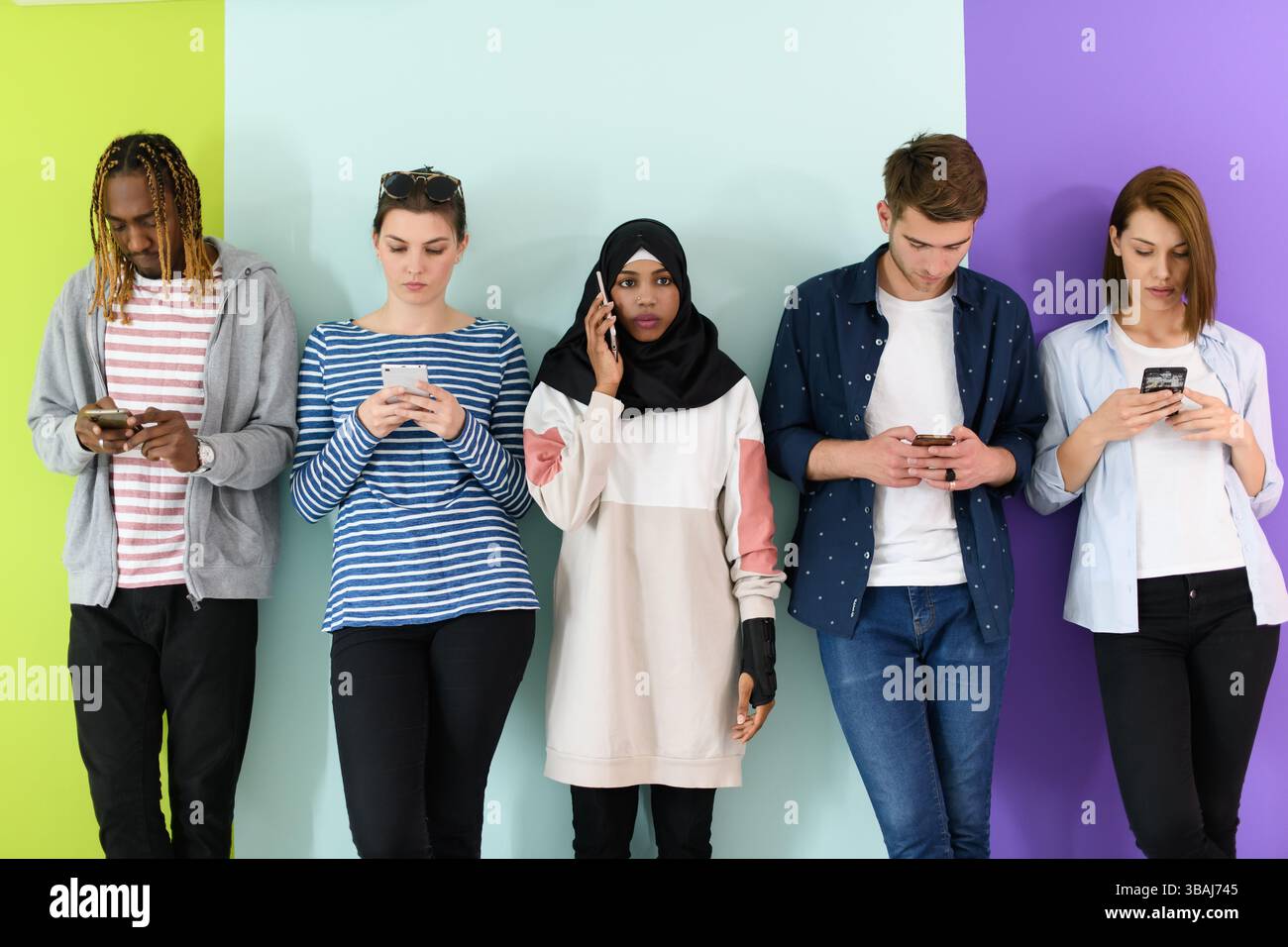Diverse group of friends using their smartphones while standing ...