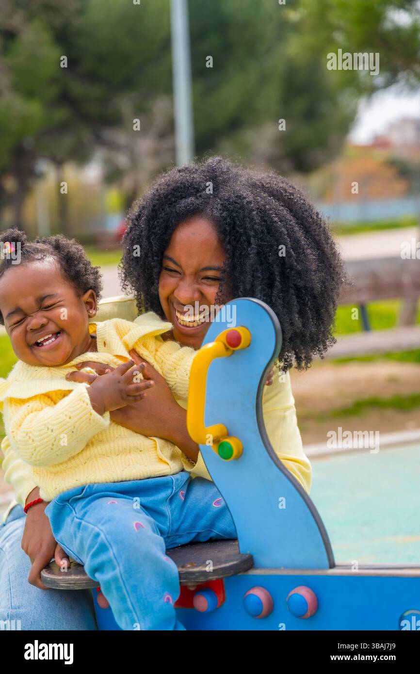 Vertical three quarter length photo of a happy african mother and daughter having fun in the ...