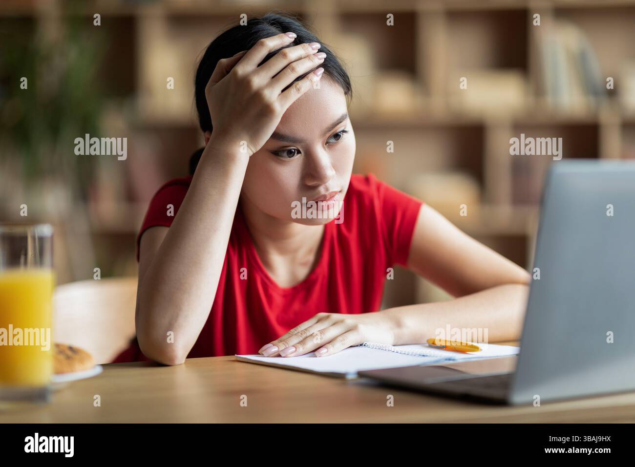Tired unhappy pretty young asian woman student looking at laptop in ...