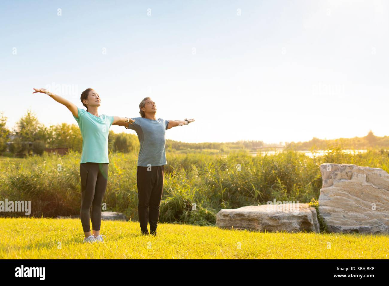 Middle-aged Chinese couple with outstretched arms doing exercise ...