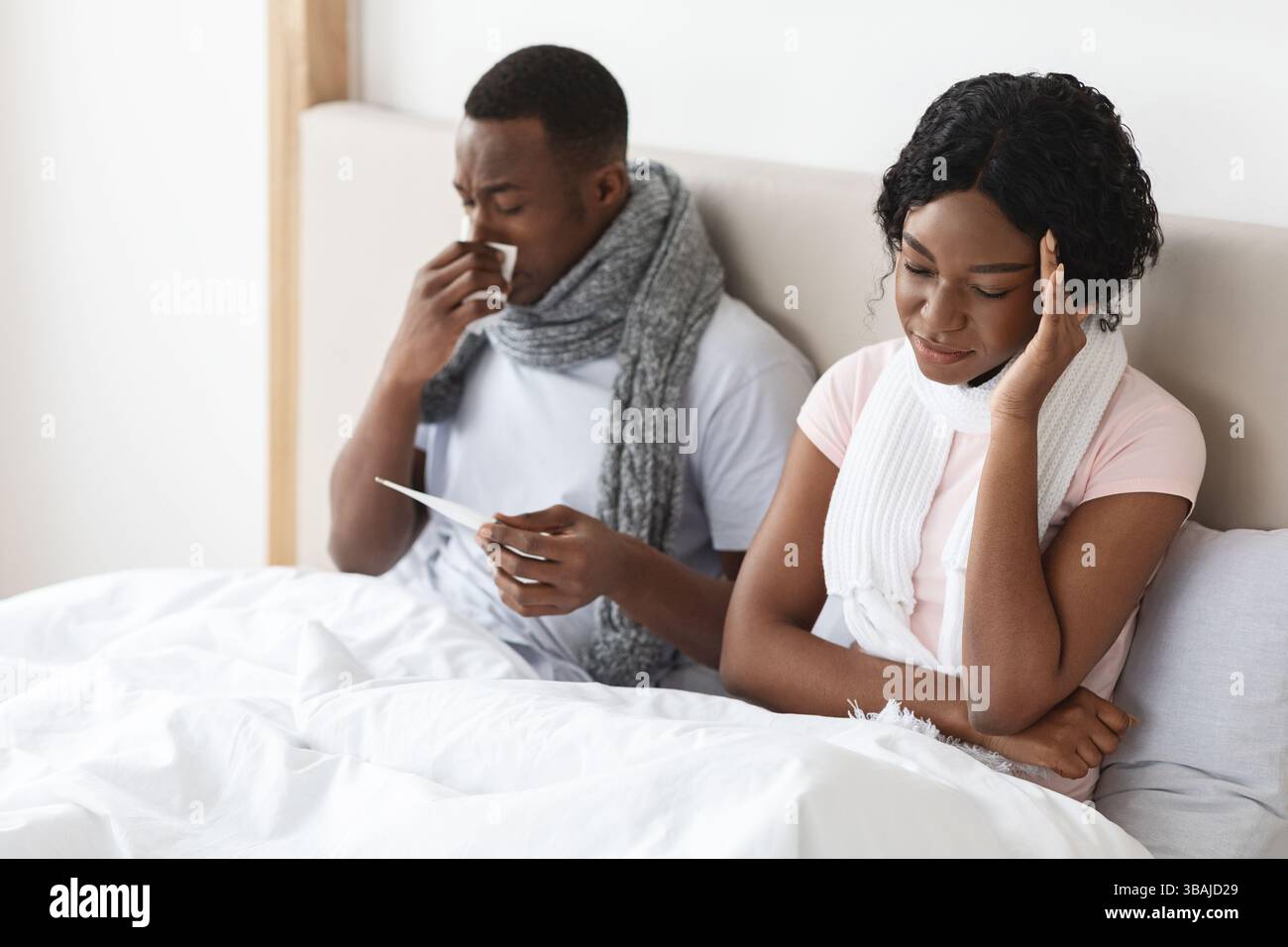 Sick african american couple wrapped in scarfs sitting in bed at ...