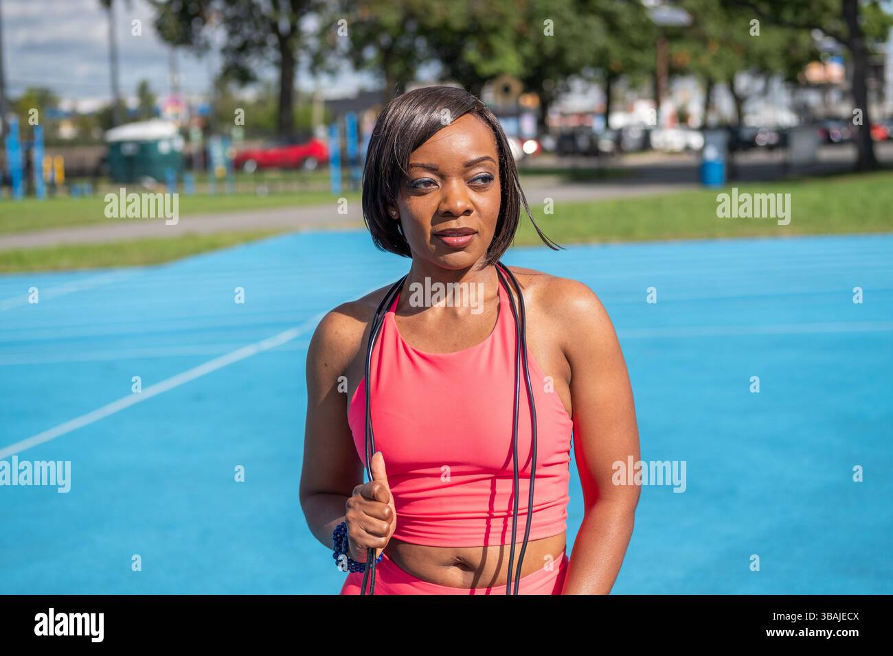 Serious Black woman in pink activewear looking away while standing with ...
