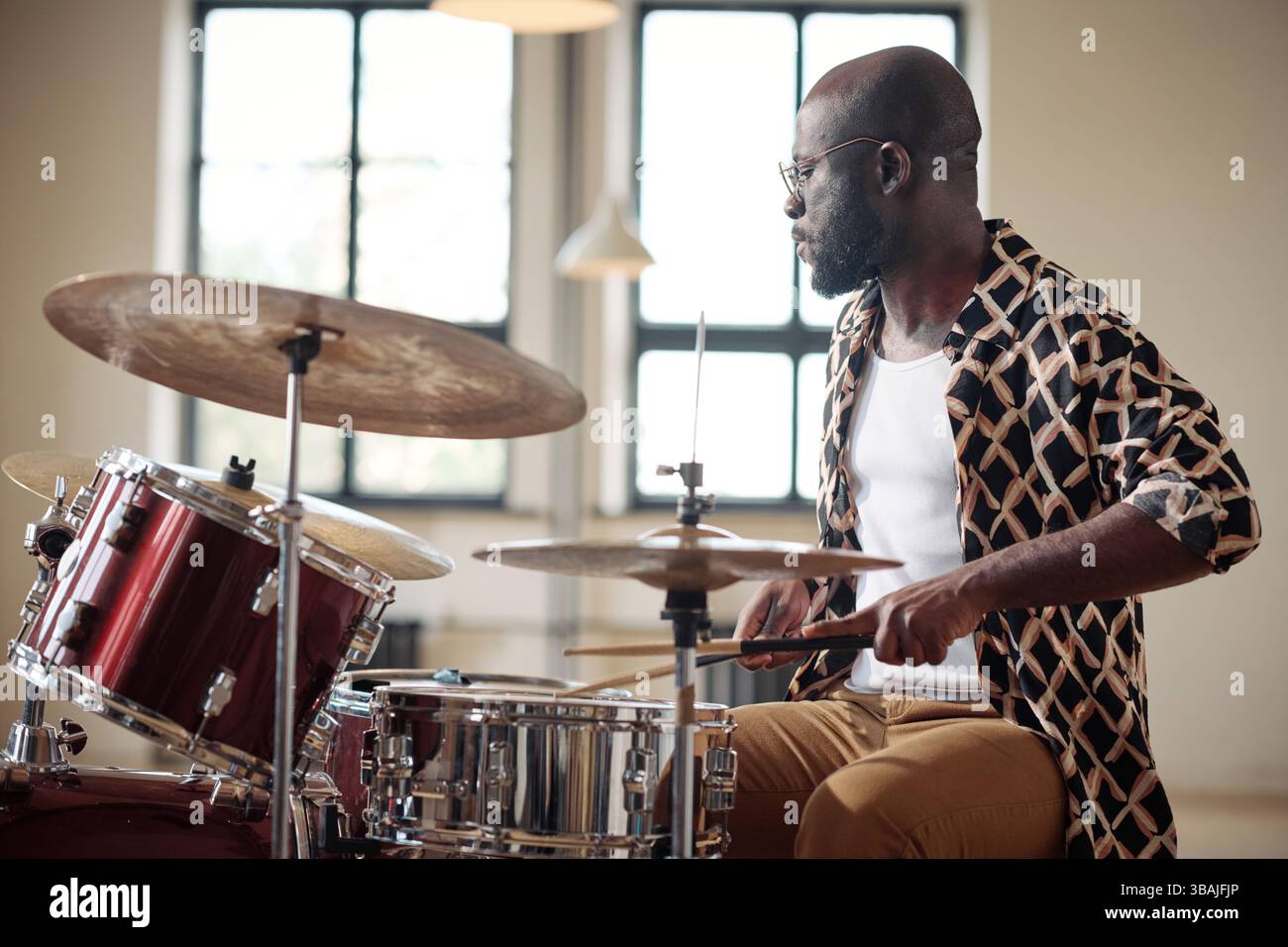 Serious African drummer recording music sitting at drums set during ...