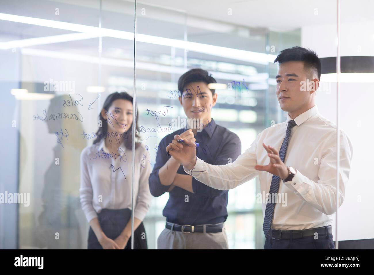 Chinese businessman discussing work with colleagues standing behind ...